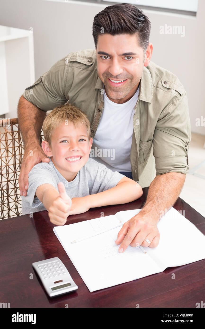Happy father helping son with his math homework at table at home in ...