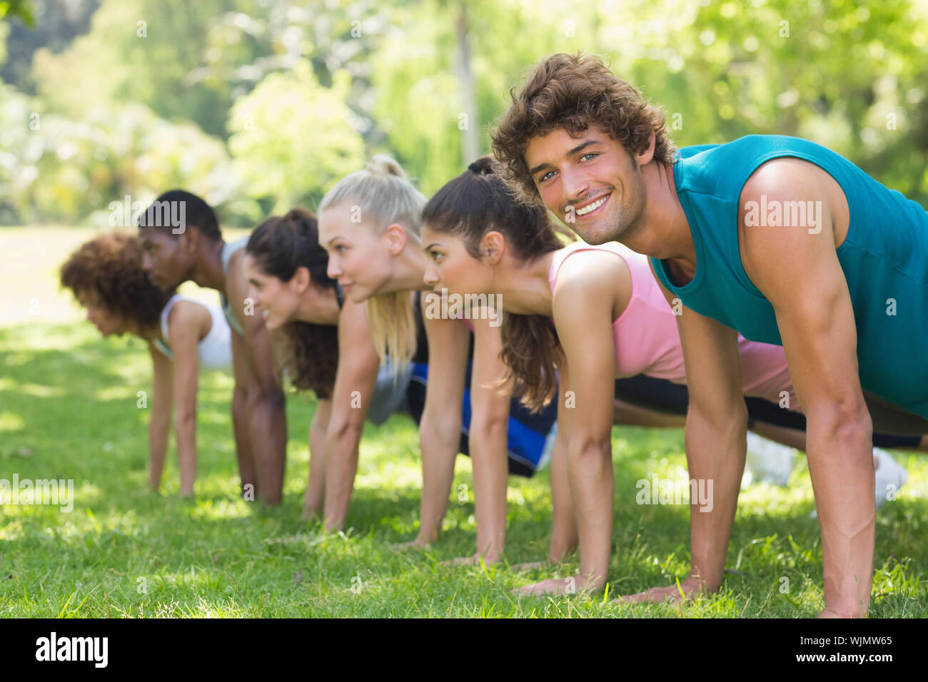 Side view of a group of fitness people doing push ups in the park Stock ...
