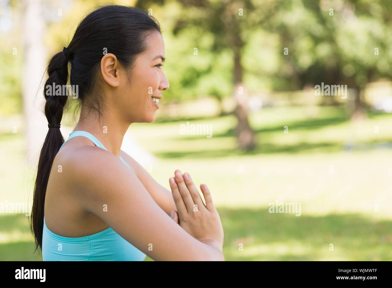 Side view of a sporty young woman in Namaste position at the park Stock ...