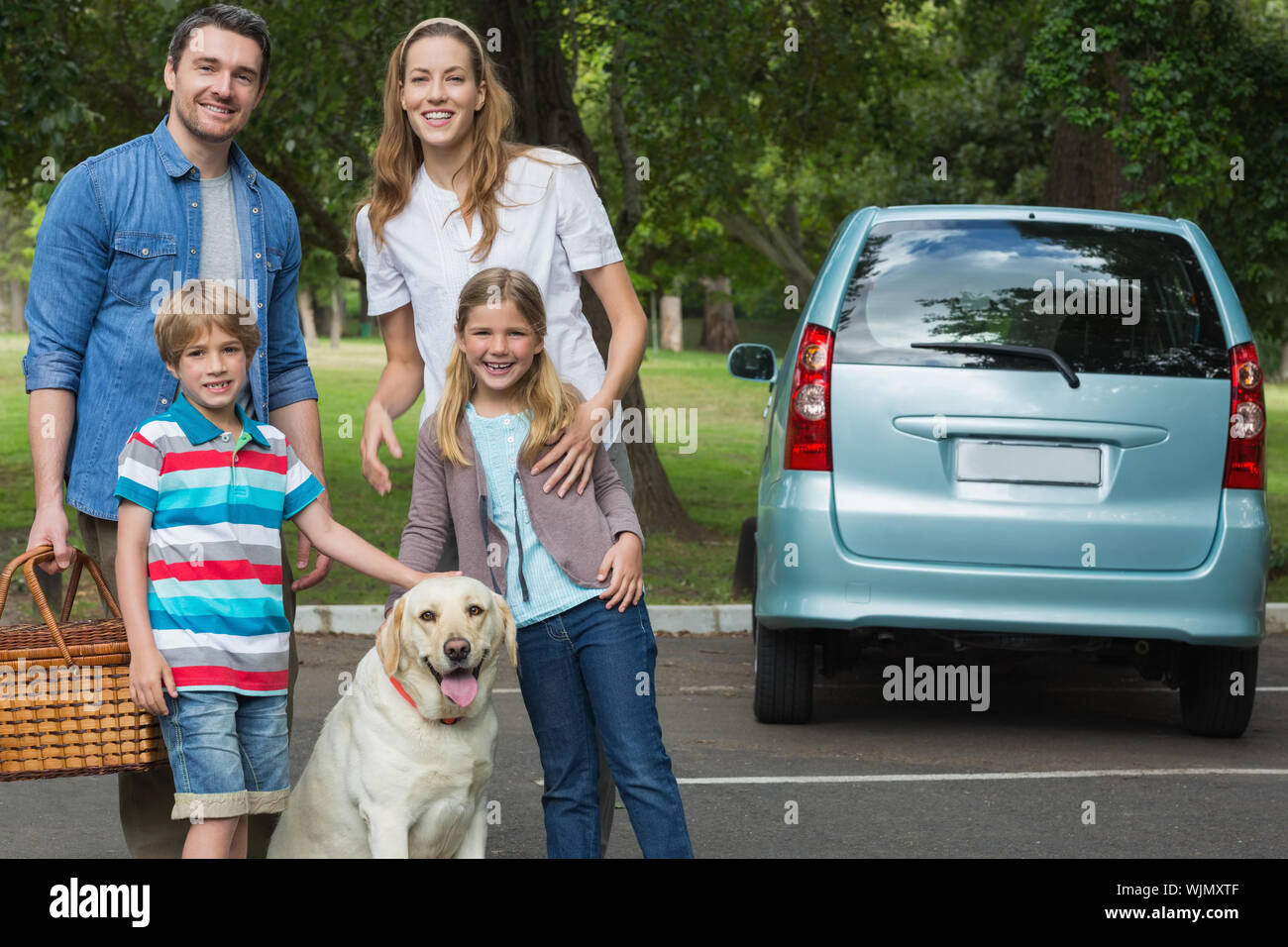 Portrait of a happy family of four with car at picnic Stock Photo - Alamy