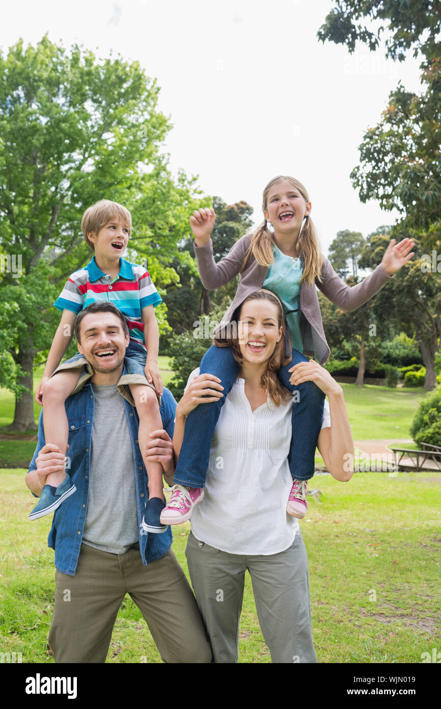 Portrait of happy parents carrying kids on shoulders at the park Stock ...