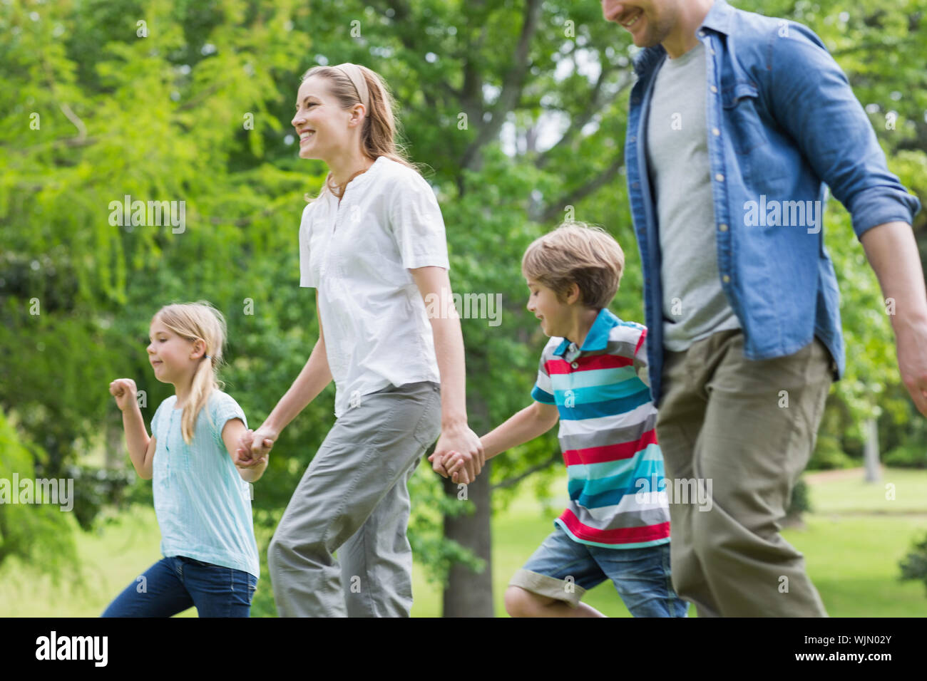 Side view of parents and kids walking in the park Stock Photo - Alamy