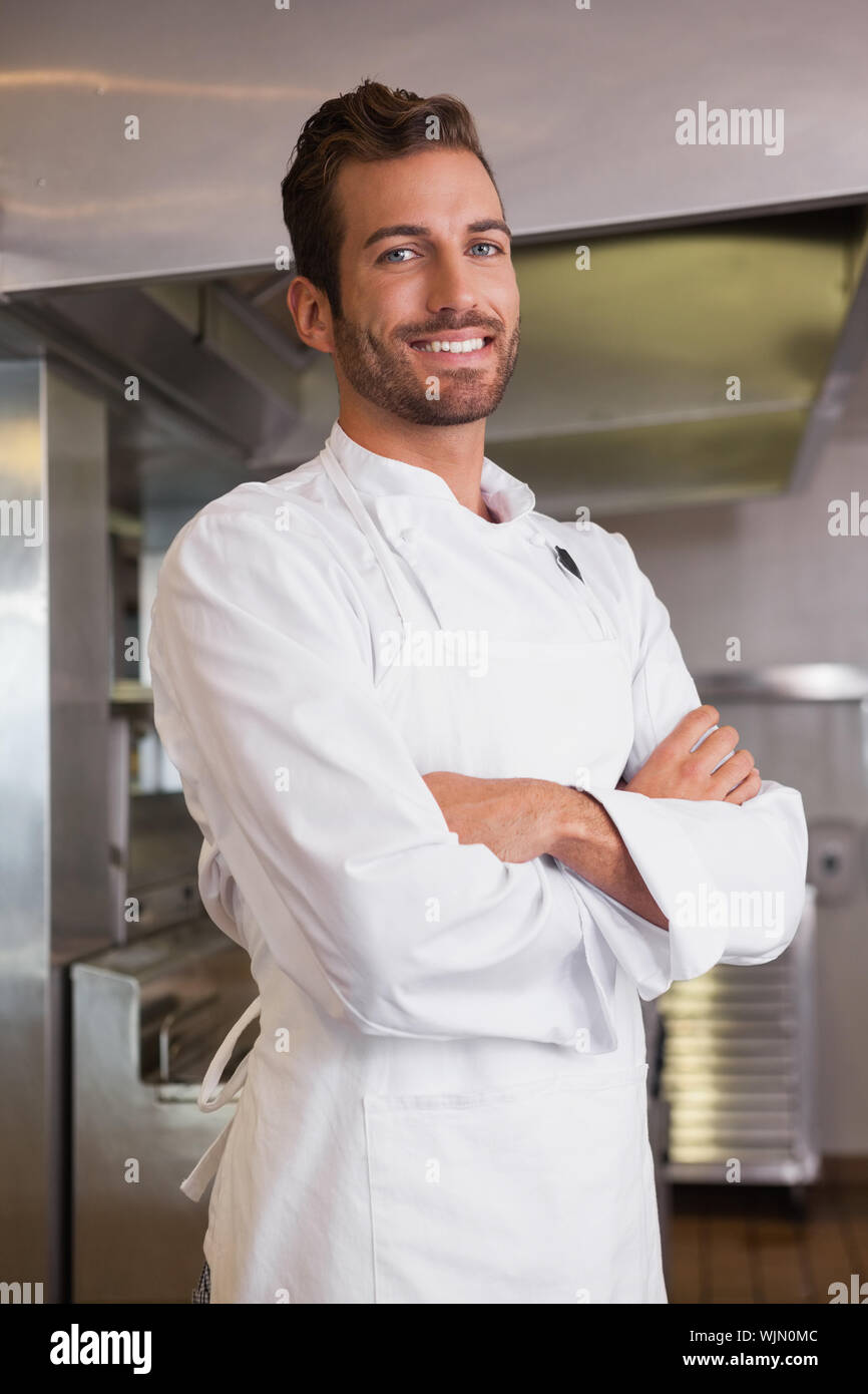 Happy chef standing with arms crossed in a commercial kitchen Stock ...