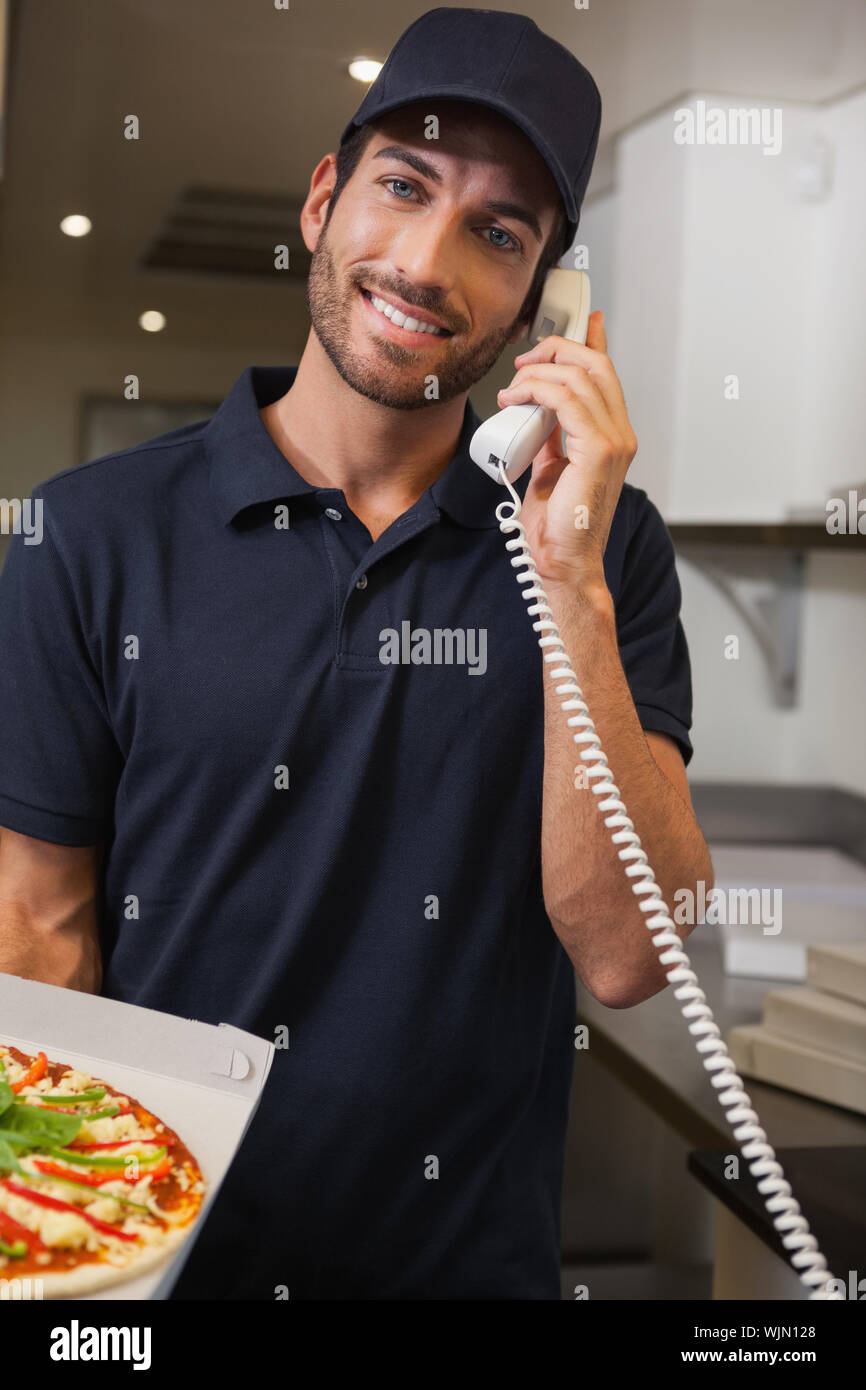 Happy pizza delivery man taking an order over the phone in a commercial ...