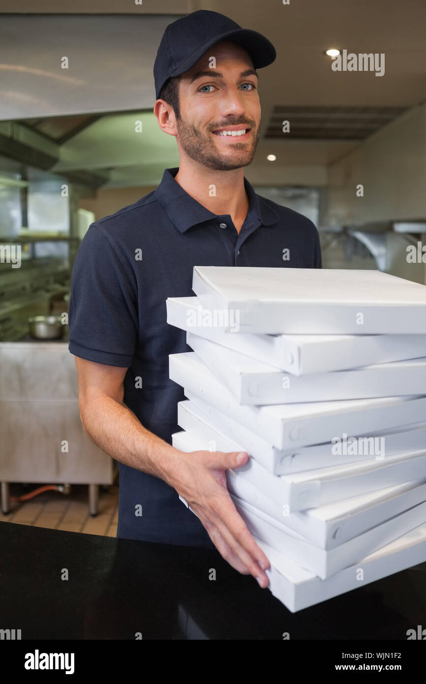 Happy pizza delivery man holding many pizza boxes in a commercial ...