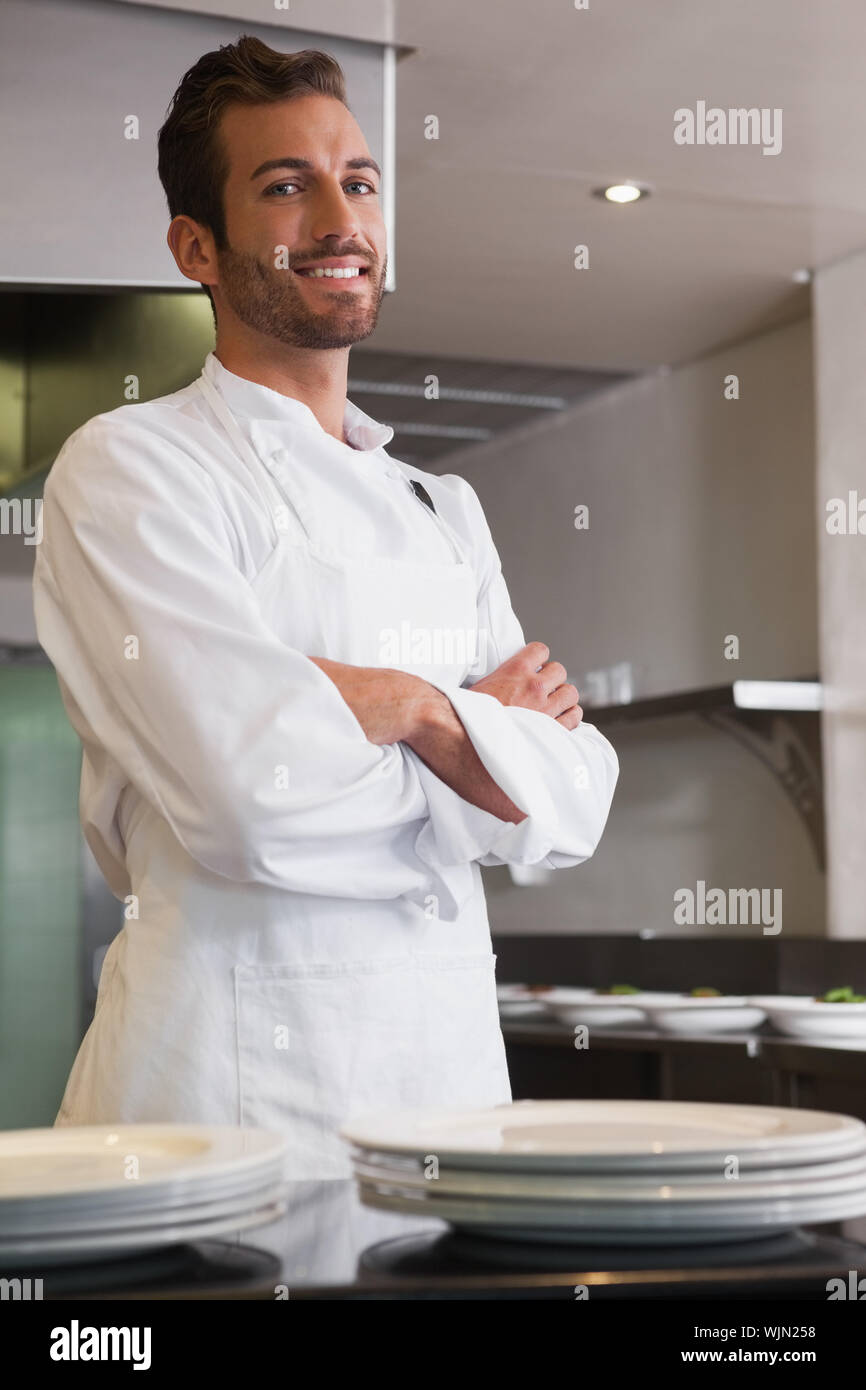Happy young chef standing with arms crossed behind counter in a ...