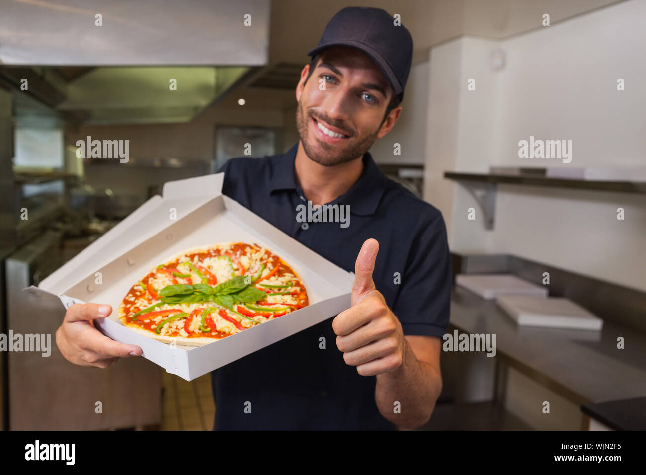 Happy pizza delivery man showing fresh pizza and thumbs up in a ...