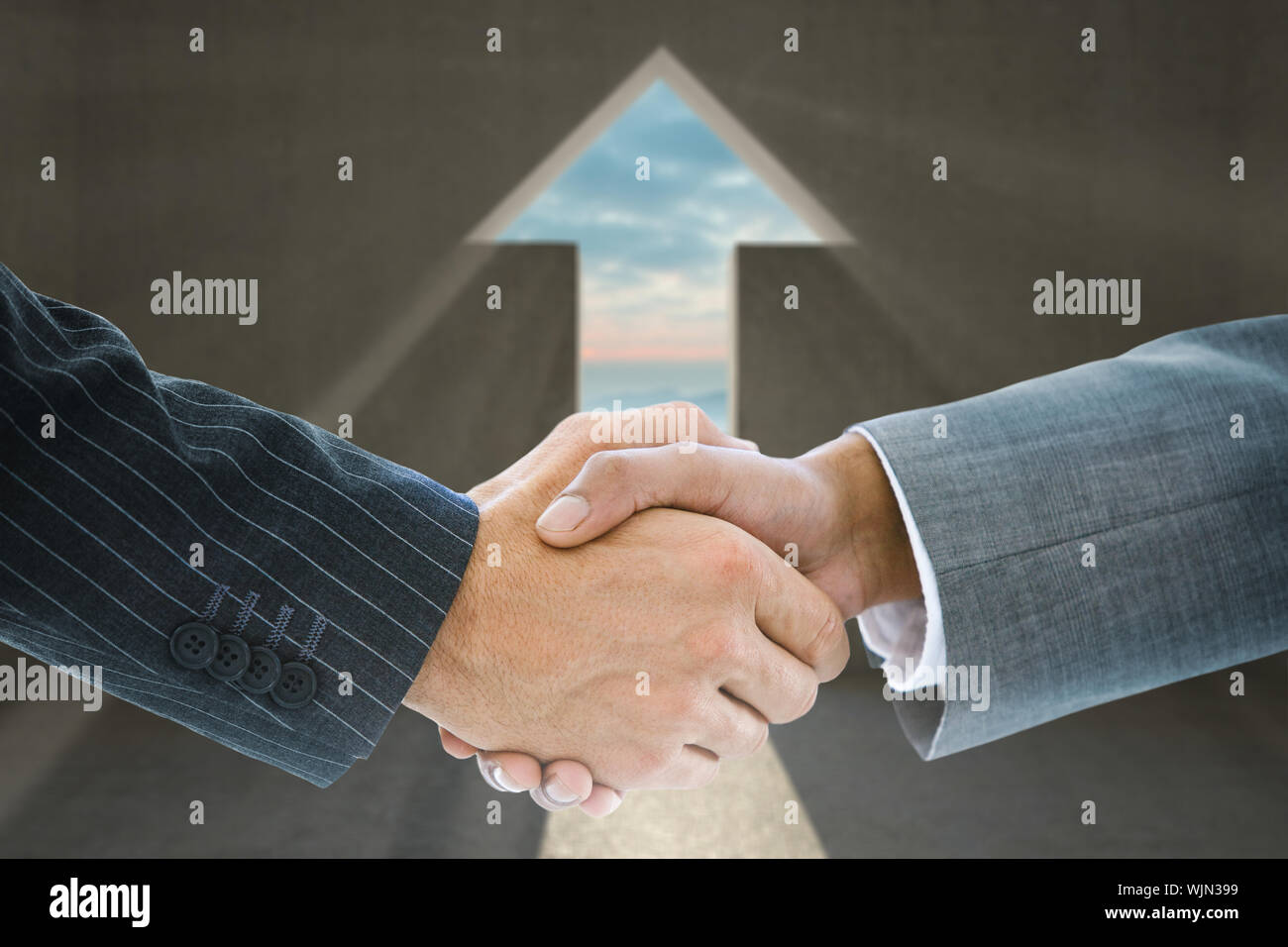 Composite image of business handshake against arrow door in dark room ...
