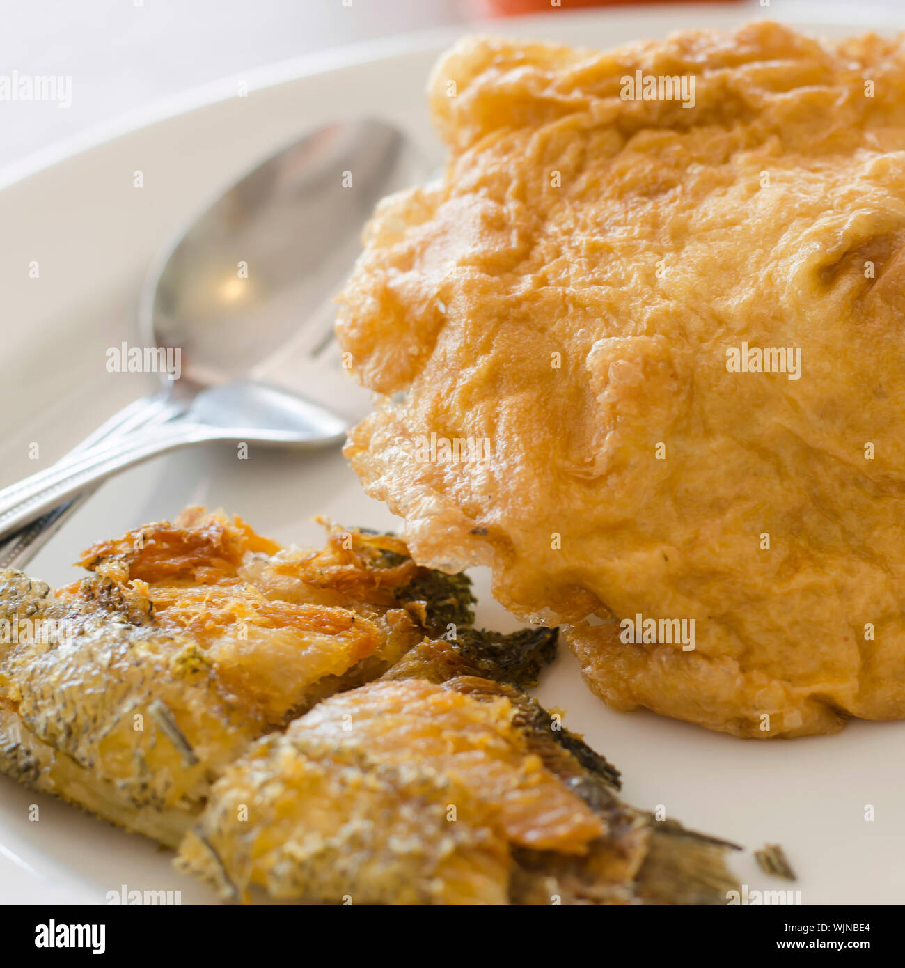 fried fish and omelet in dish with spoon and fork Stock Photo - Alamy