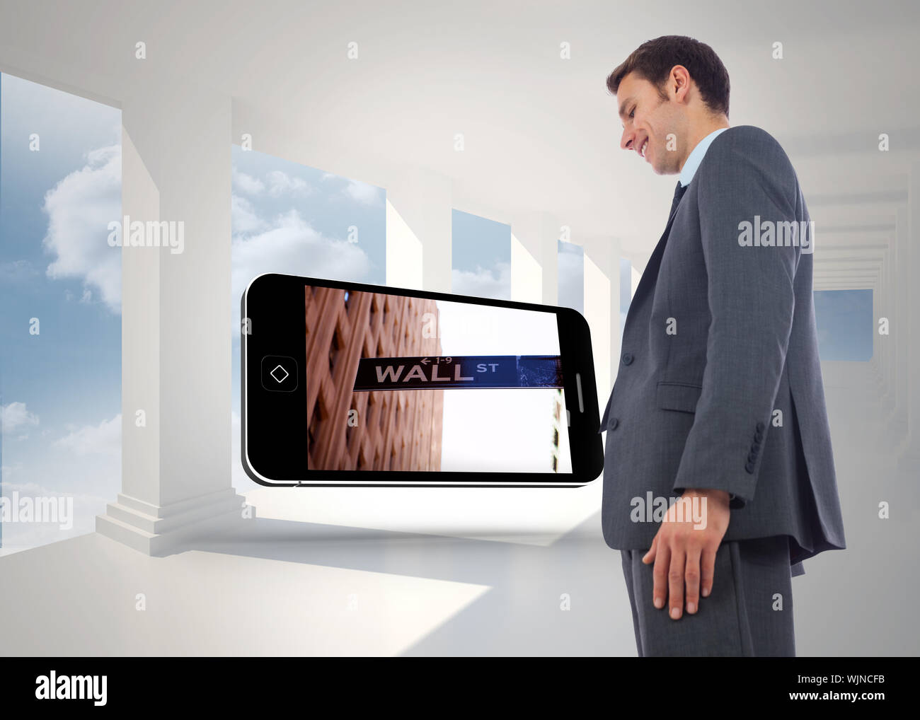 Cheerful handsome businessman standing against bright white hall with ...