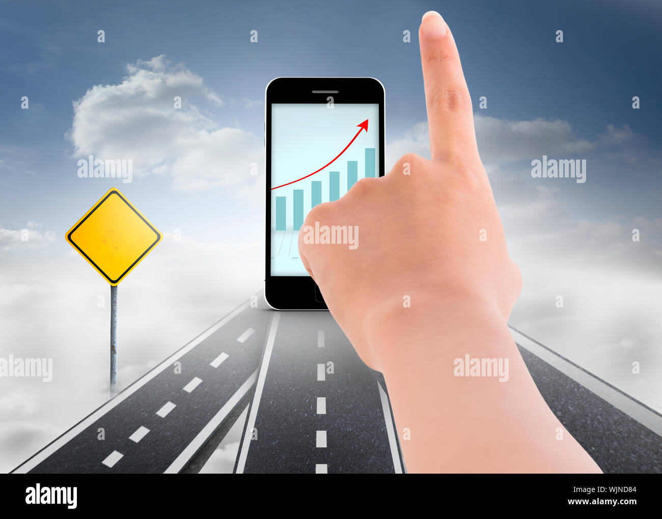 Female hand pointing against road over clouds with road signs on it ...