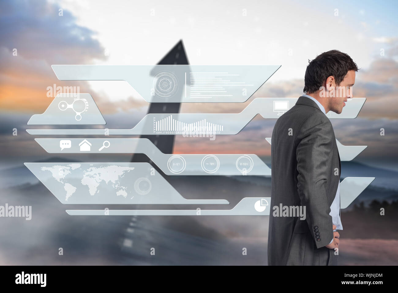 Smiling businessman with hand on hip against road turning into arrow Stock Photo - Alamy