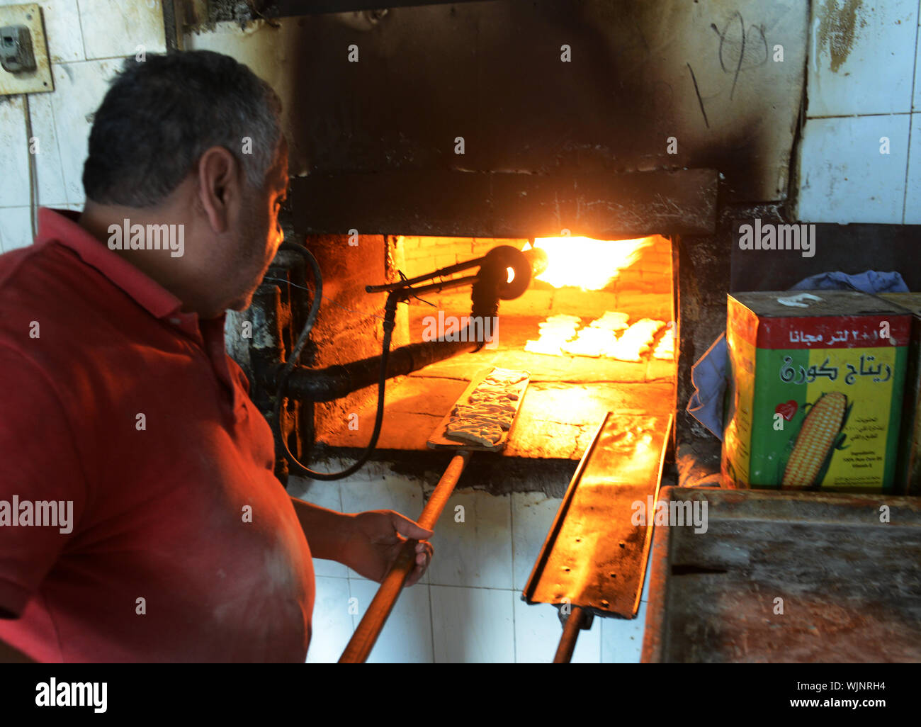 A Jordanian baker baking traditional Sambousek in a fire oven in Madaba ...