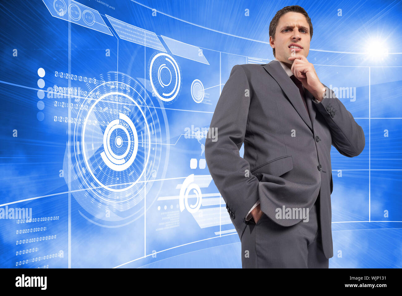 Thoughtful businessman with hand on chin against futuristic technology ...