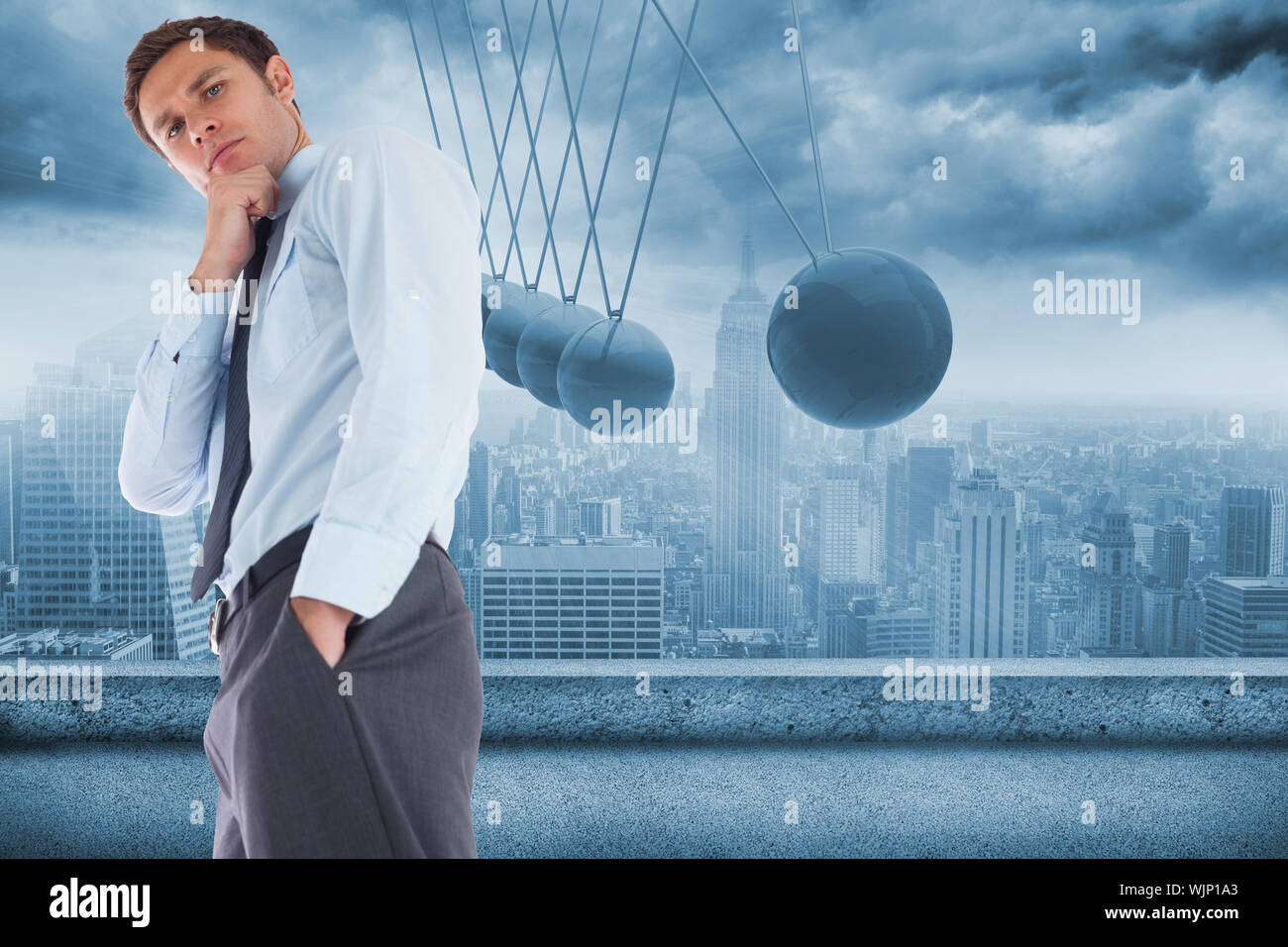 Thoughtful businessman with hand on chin against newtons cradle above ...