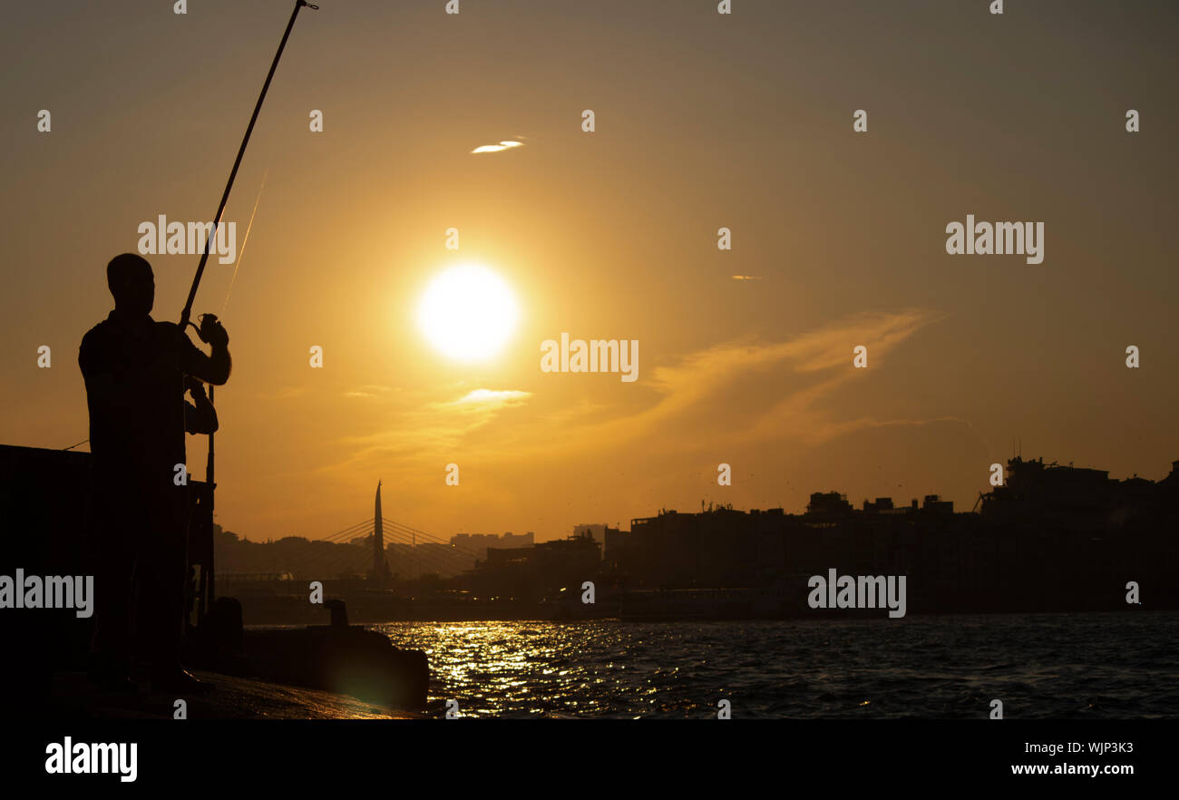 Sunset silhouette of holding fish Stock Photo - Alamy