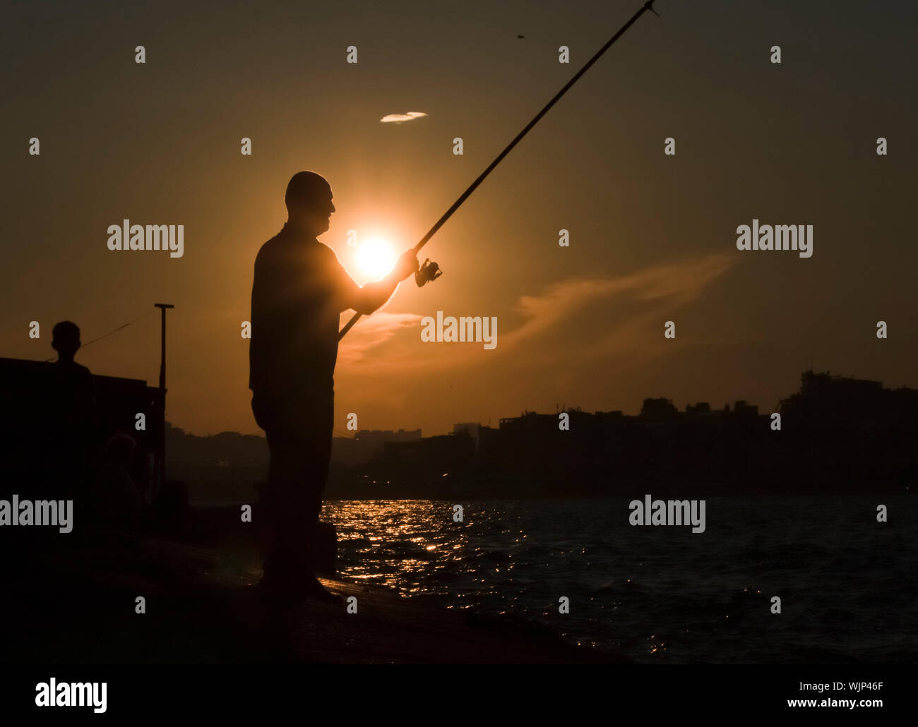 Sunset silhouette of holding fish Stock Photo - Alamy