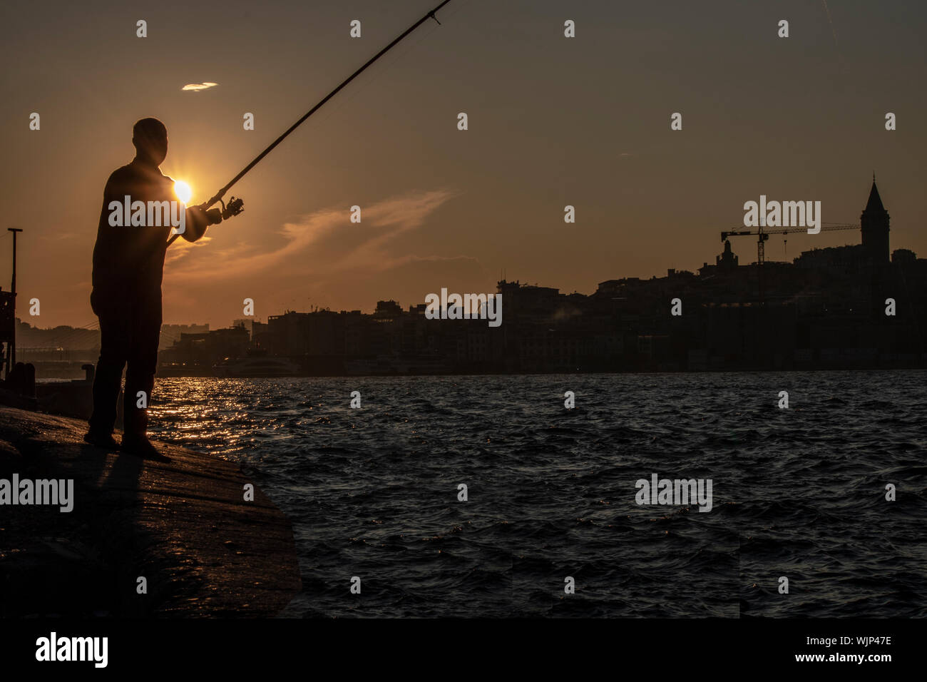 Sunset silhouette of holding fish Stock Photo - Alamy