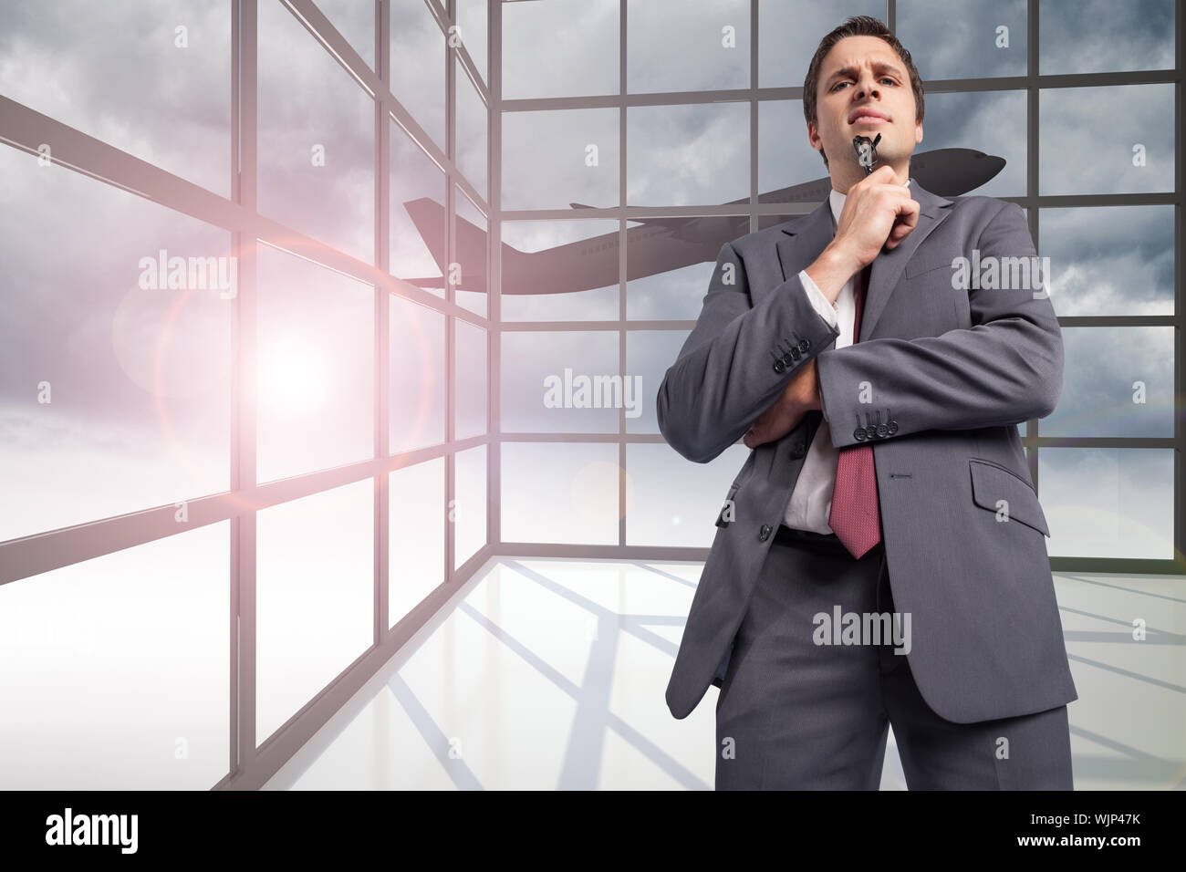 Thinking businessman holding his glasses against airplane flying past ...