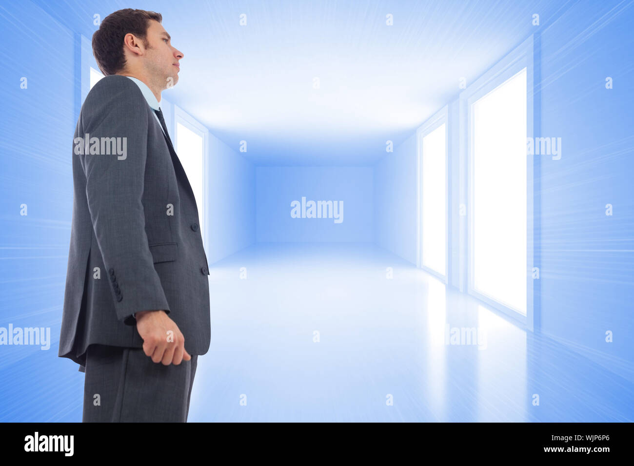 Stern businessman standing against bright blue hall with windows Stock ...