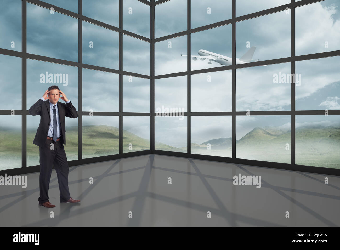 Stressed businessman with hands on head against airplane flying past ...