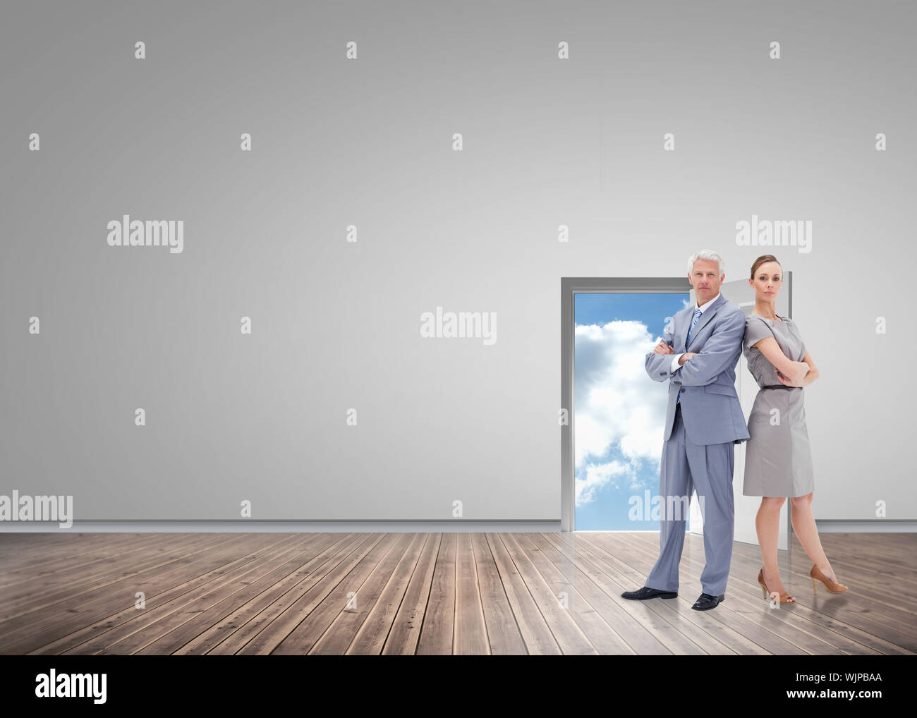 Serious businessman standing back to back with a woman against door ...
