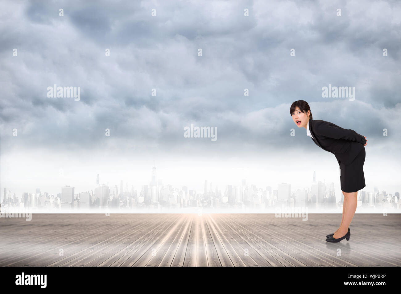 Surprised businesswoman bending against city on the horizon Stock Photo ...