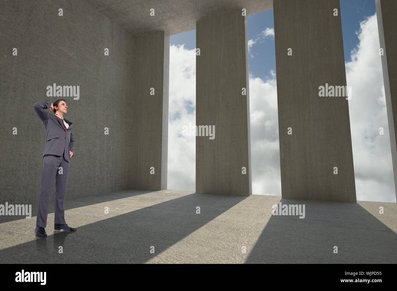 Thinking businessman scratching head against light shining into dark ...