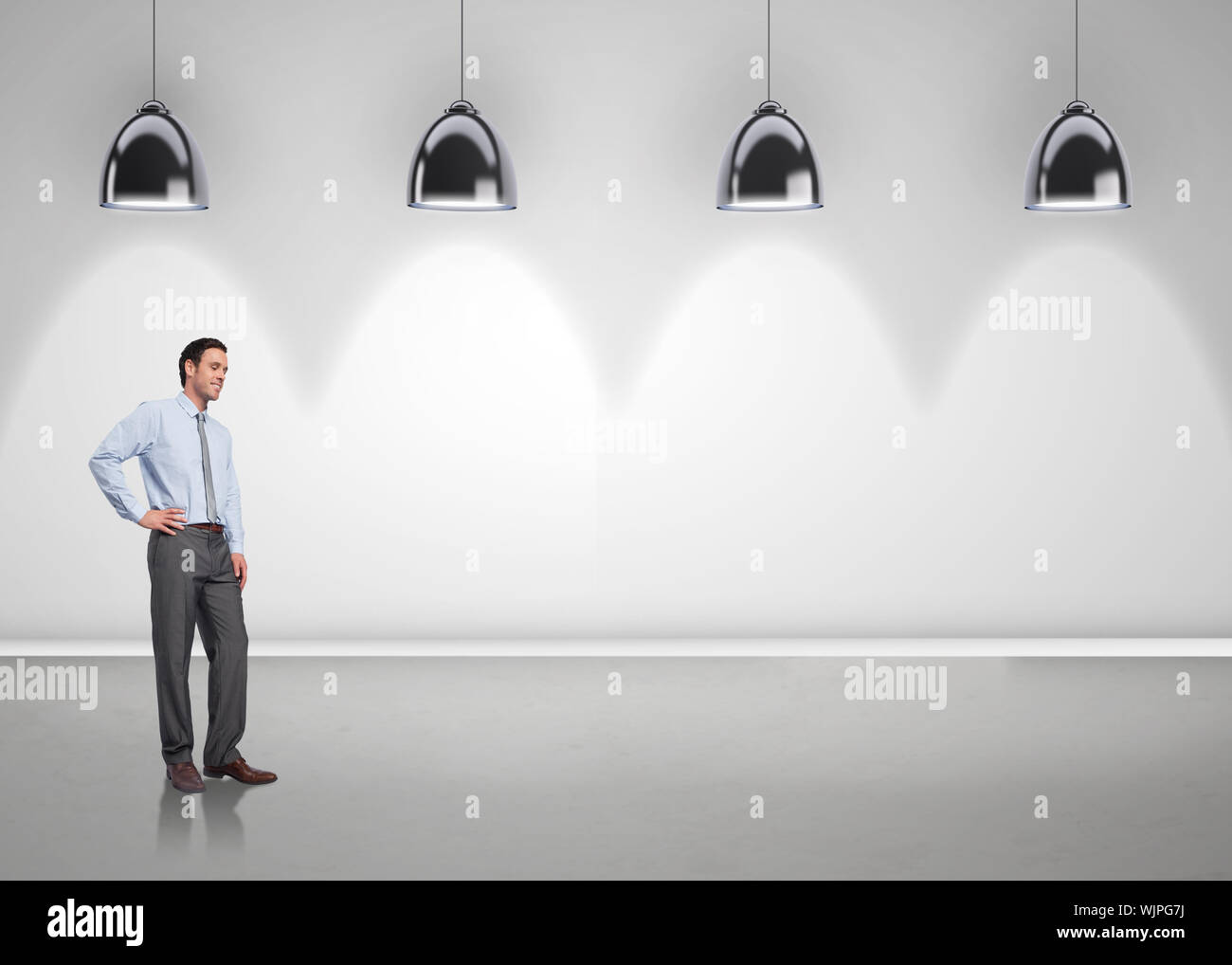 Smiling businessman with hand on hip against grey room Stock Photo - Alamy