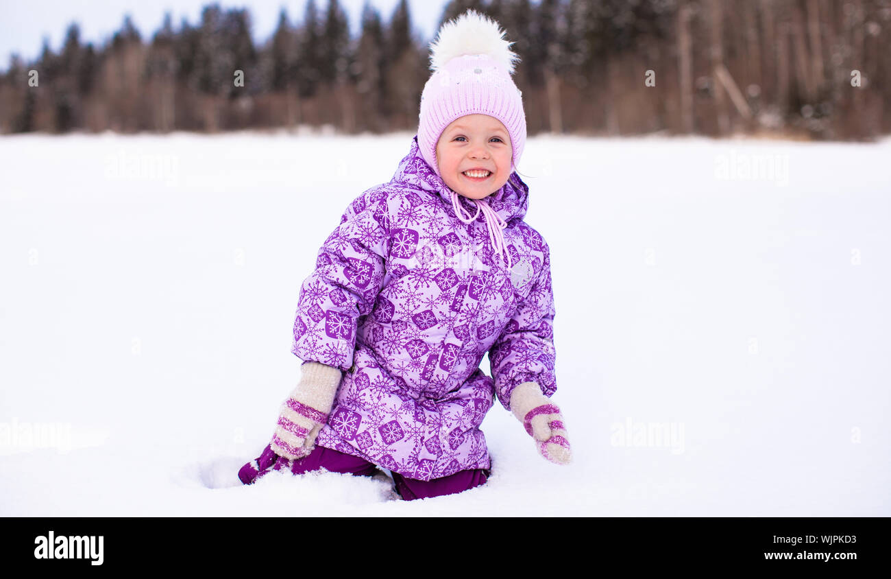 Little happy adorable girl having fun on the snow at winter sunny day ...