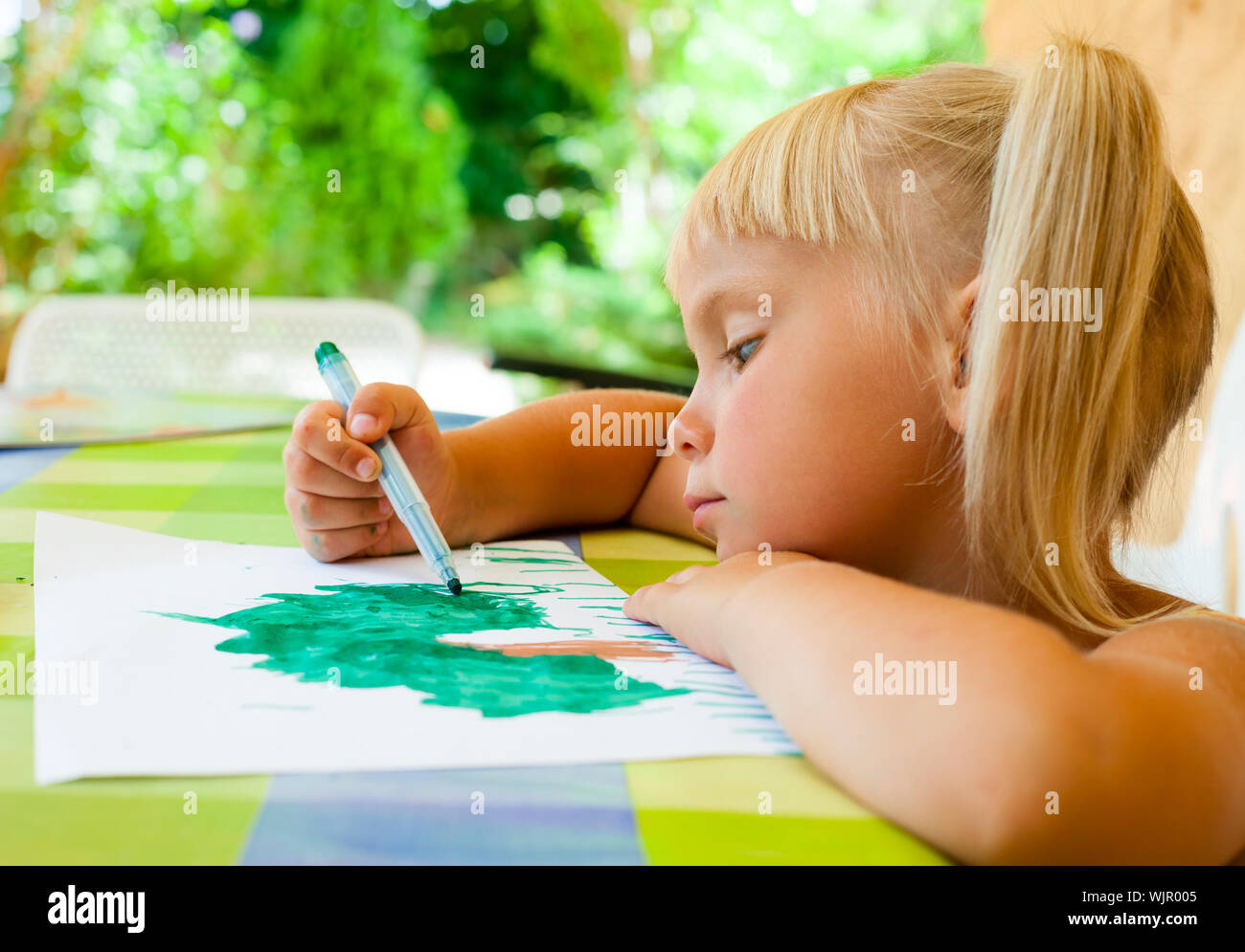 Cute 4 year old girl sitting at table drawing a tree Stock Photo - Alamy