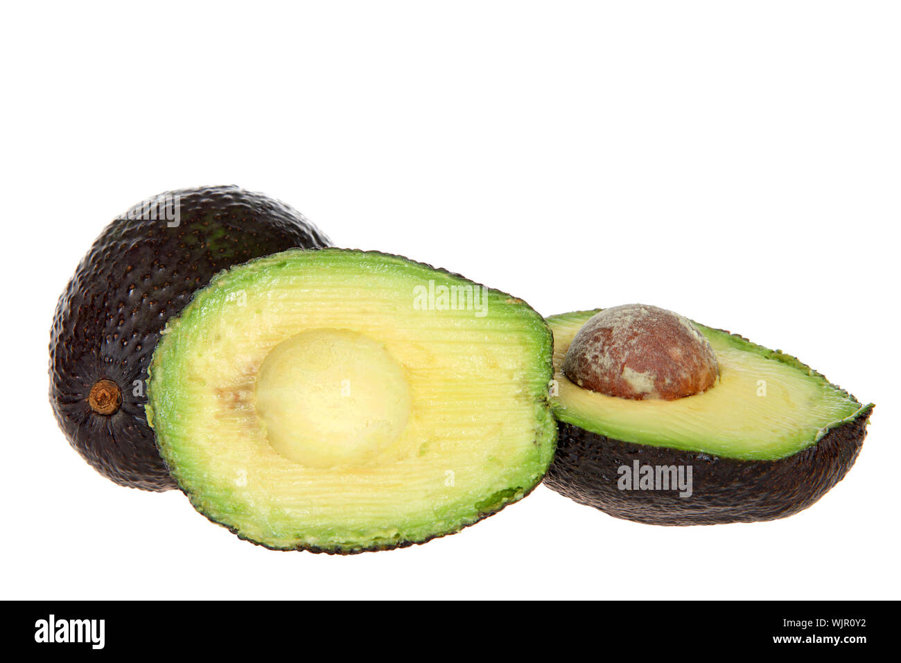 whole avocado and one cut with seed exposed, isolated on white ...