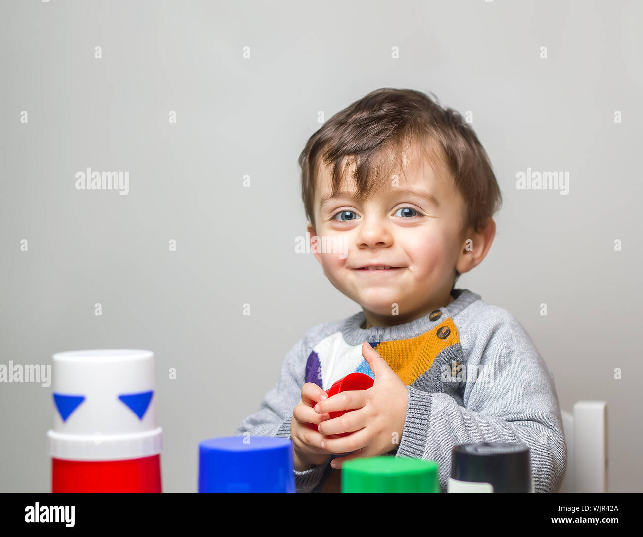 Child staring at the camera smiling while playing with toys Stock Photo ...