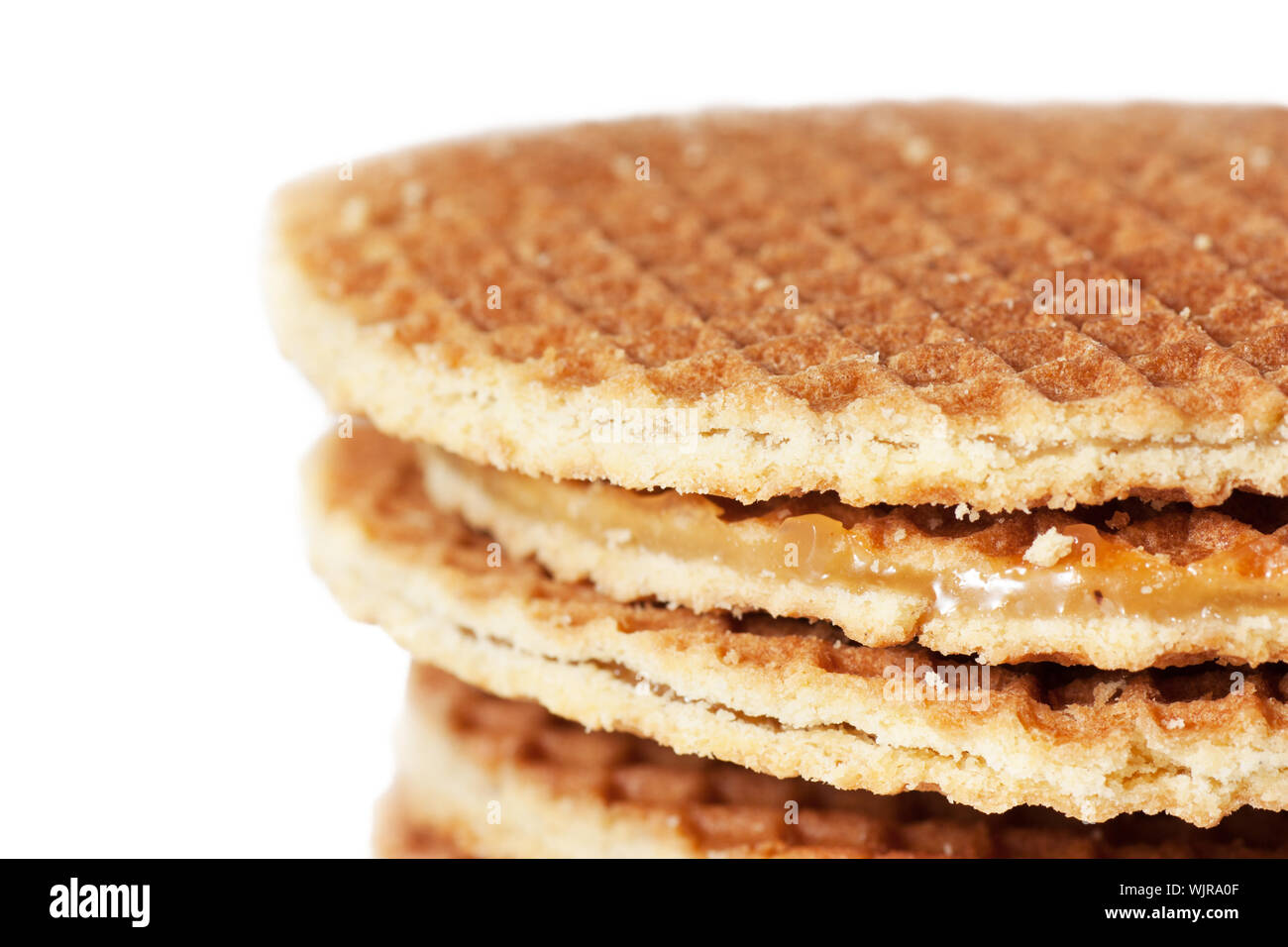 A stack of golden round waffles with caramel isolated over white ...
