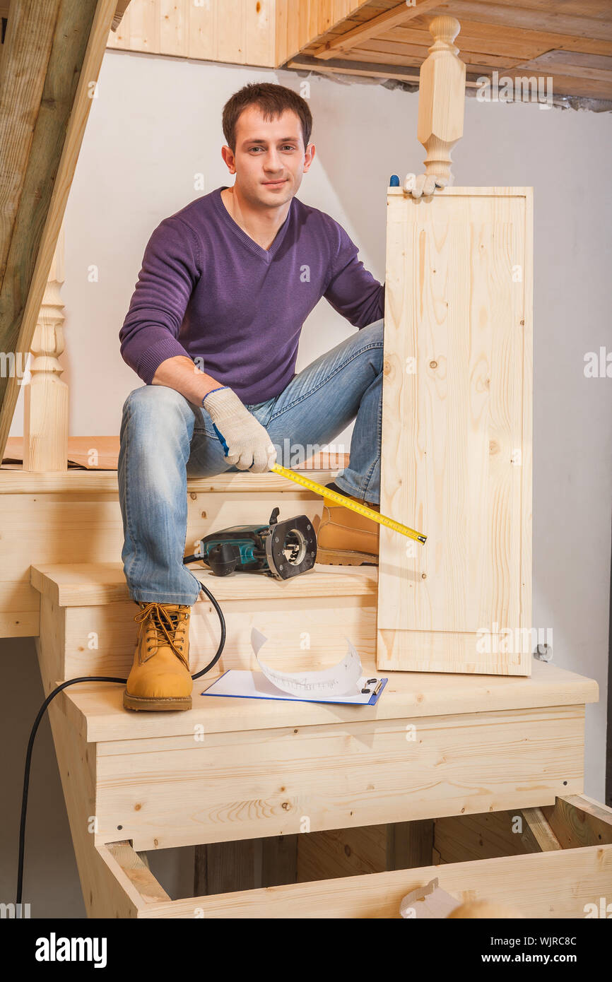 a young worker sitting on ladder and holding one step Stock Photo - Alamy