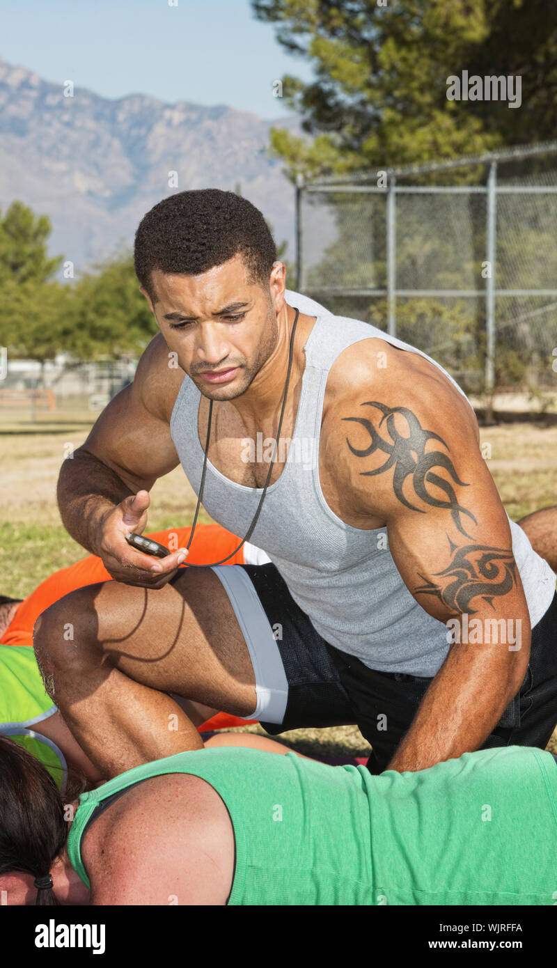 Athletic trainer with tattoo and outdoor fitness class Stock Photo - Alamy