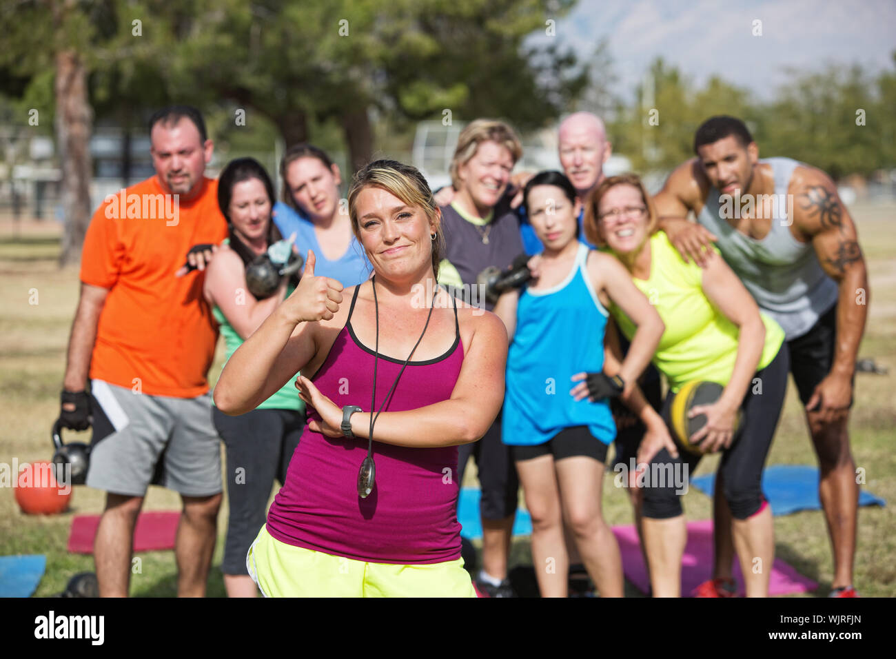 Boot camp fitness instructor with group and thumbs up Stock Photo - Alamy