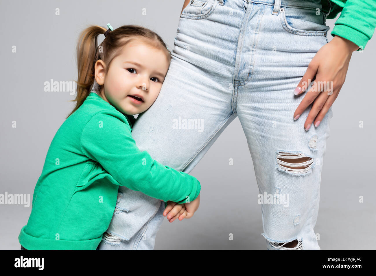 Young daughter hug mother legs on white background Stock Photo - Alamy
