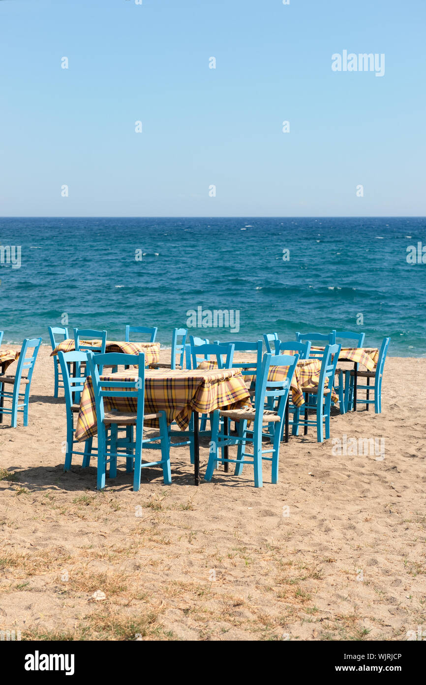 Greek beach with traditional blue table and chairs Stock Photo - Alamy