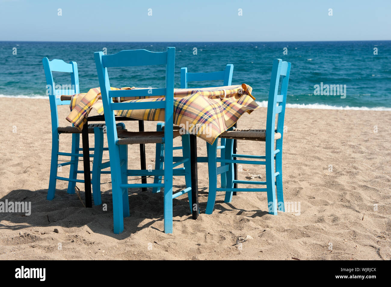 Greek beach with traditional blue table and chairs Stock Photo - Alamy