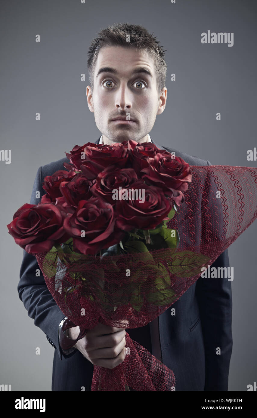 Shocked man holding out large bouquet of red roses Stock Photo - Alamy