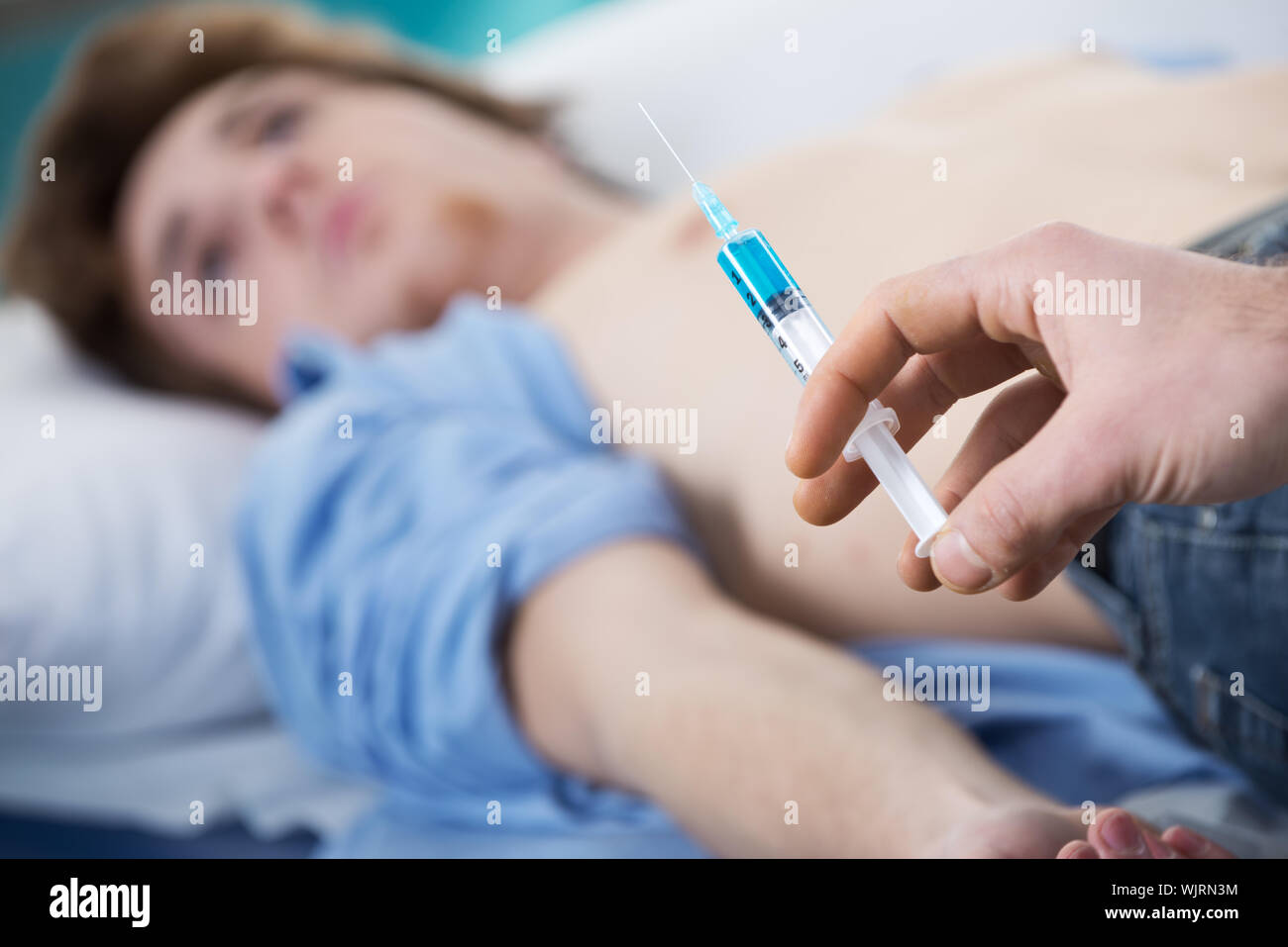 Doctor preparing a syringe for an injection with patient on the ...