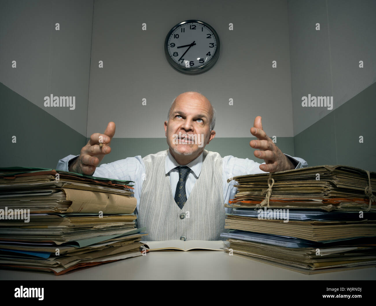 Angry office worker with piles of folders in a small room Stock Photo ...