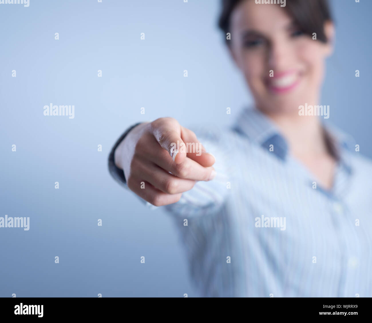 Beautiful young woman smiling and pointing at camera Stock Photo - Alamy