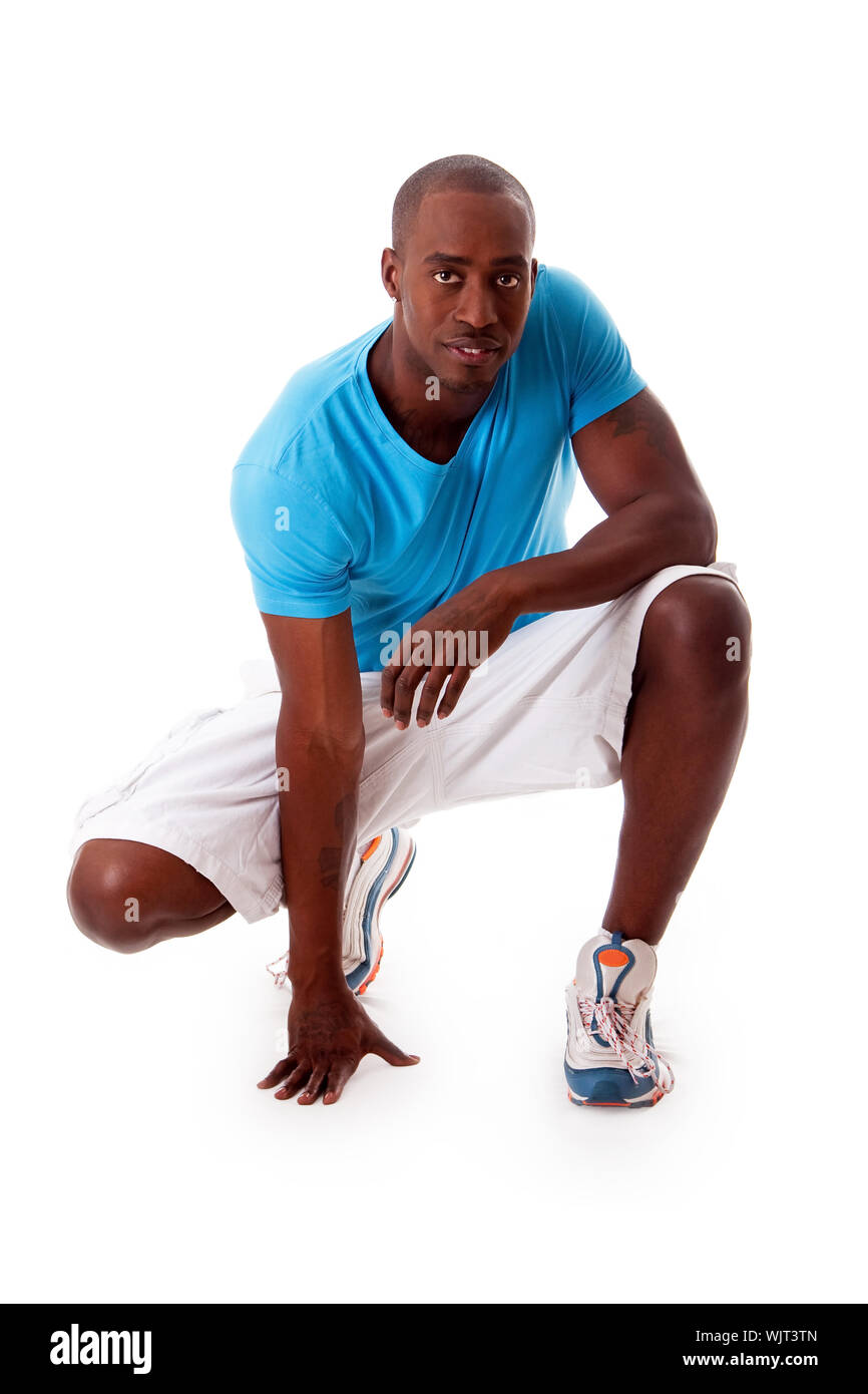 Handsome African American sporty man crouching wearing blue shirt ...