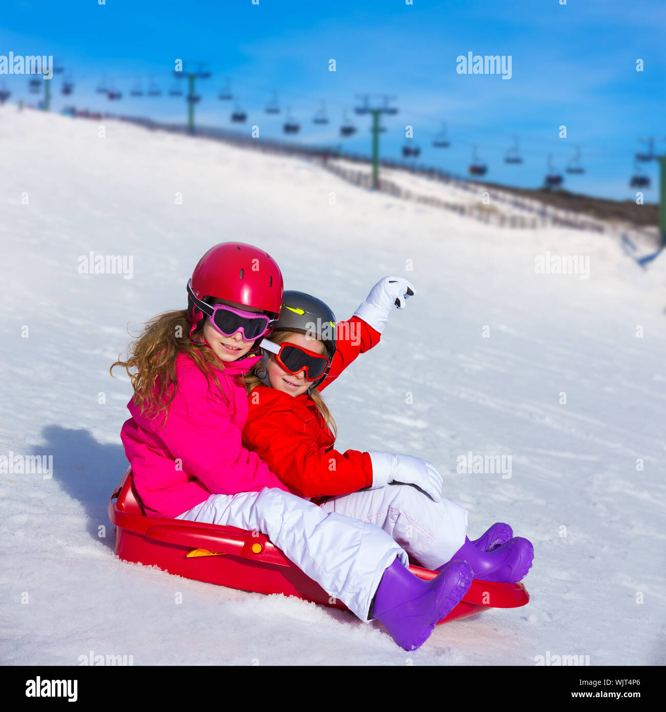 Kid girls playing sled in winter snow with helmets and goggles Stock ...