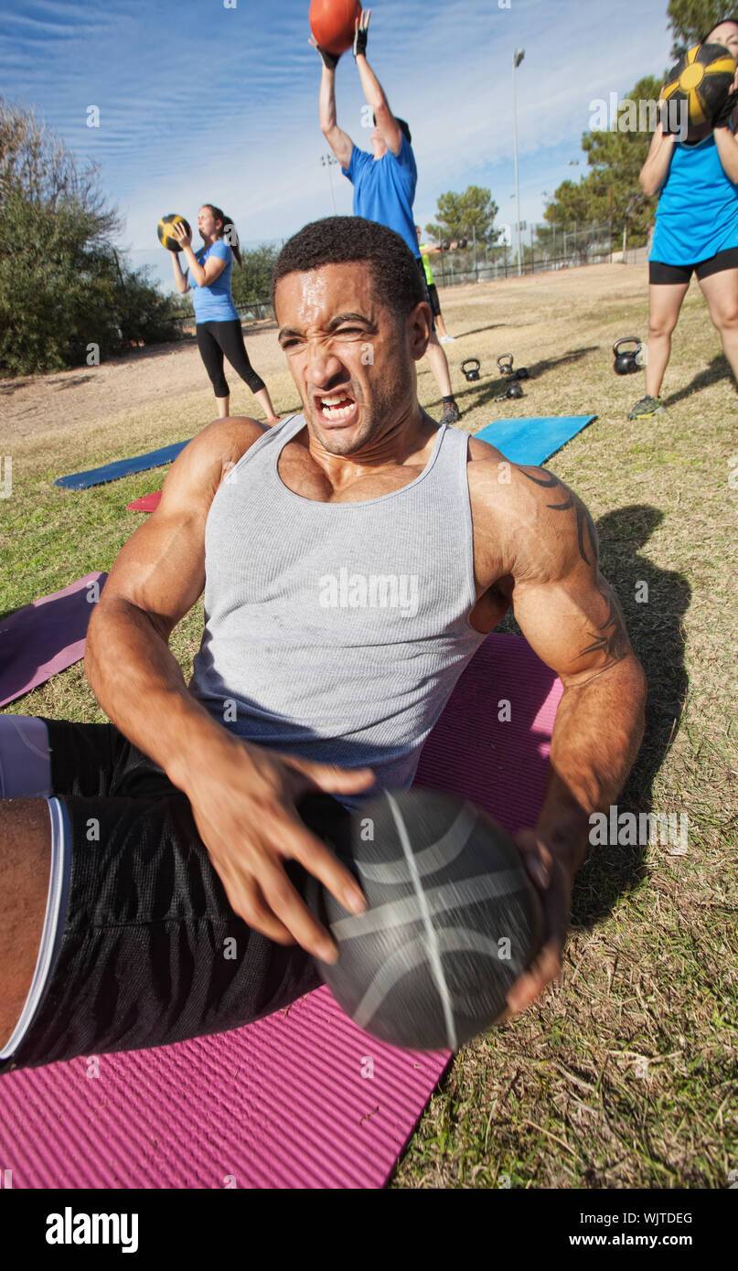 Serious muscular man doing sit-ups with medicine ball outdoors Stock ...