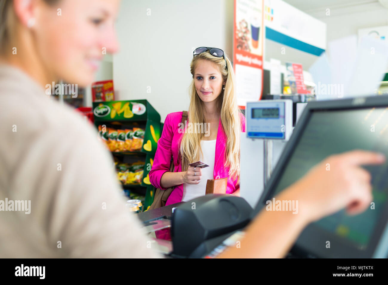 Beautiful young woman paying for her groceries at the counter of a ...