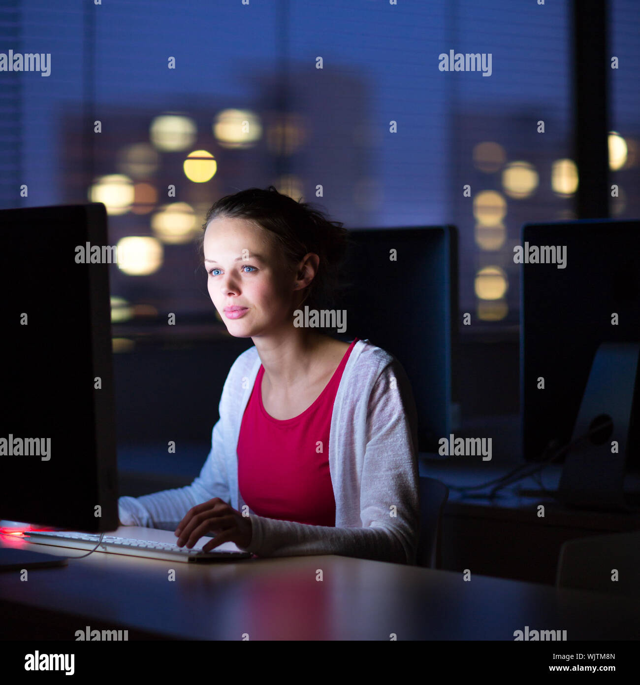 Pretty, young female college student using a desktop computer/pc in a ...