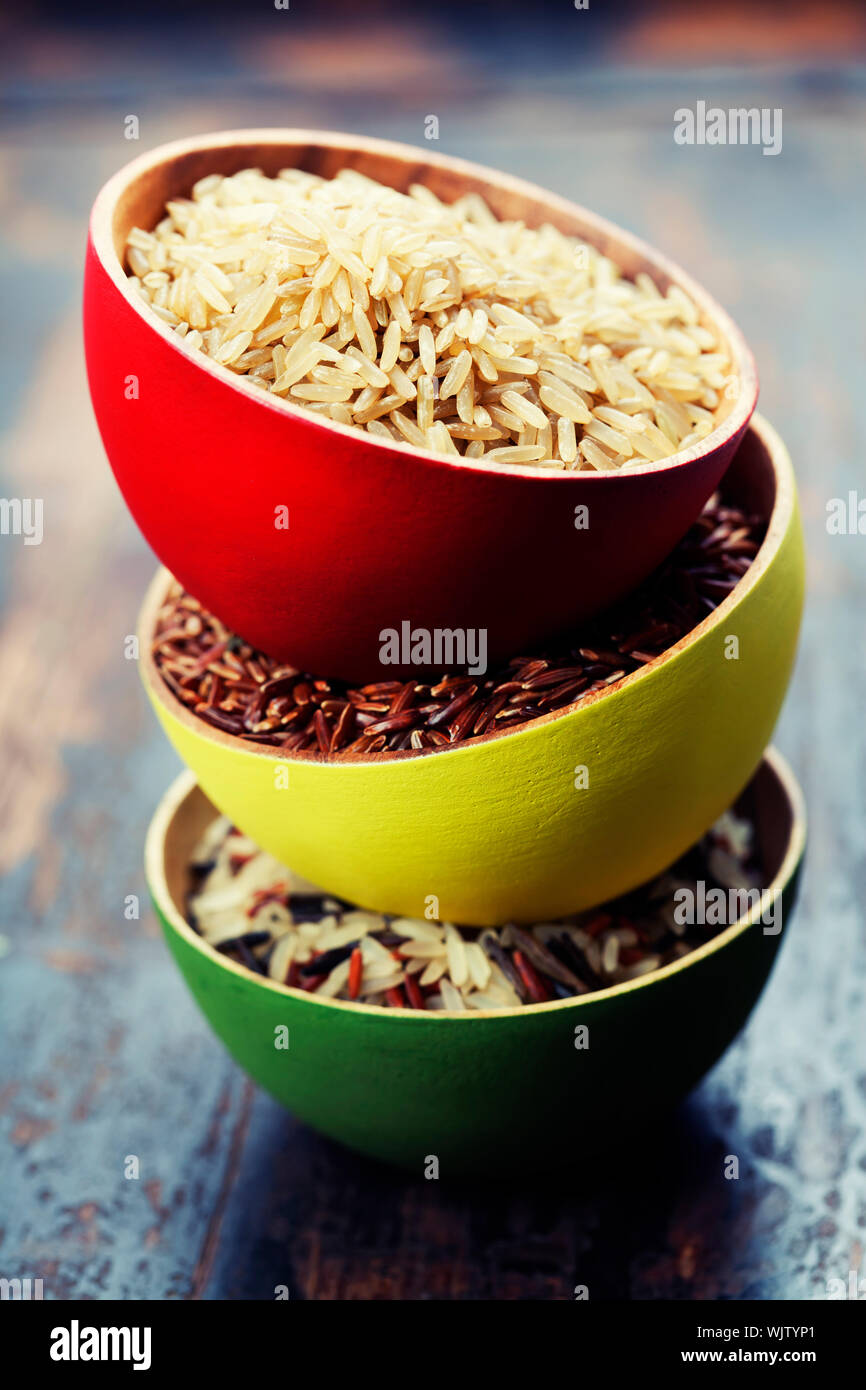 Three bowls with different types of rice on wooden background Stock ...
